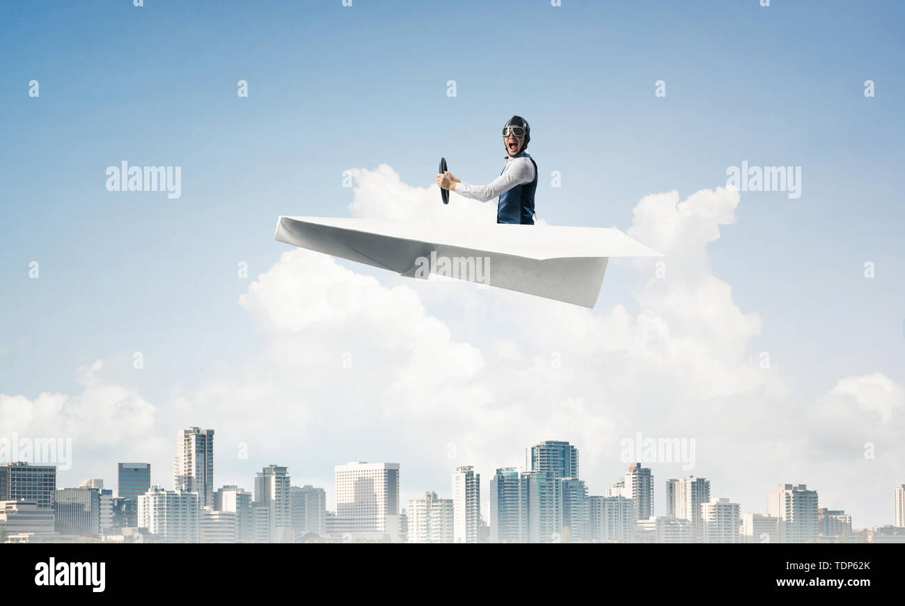 Scared pilot with open mouth sitting in paper plane and holding ...