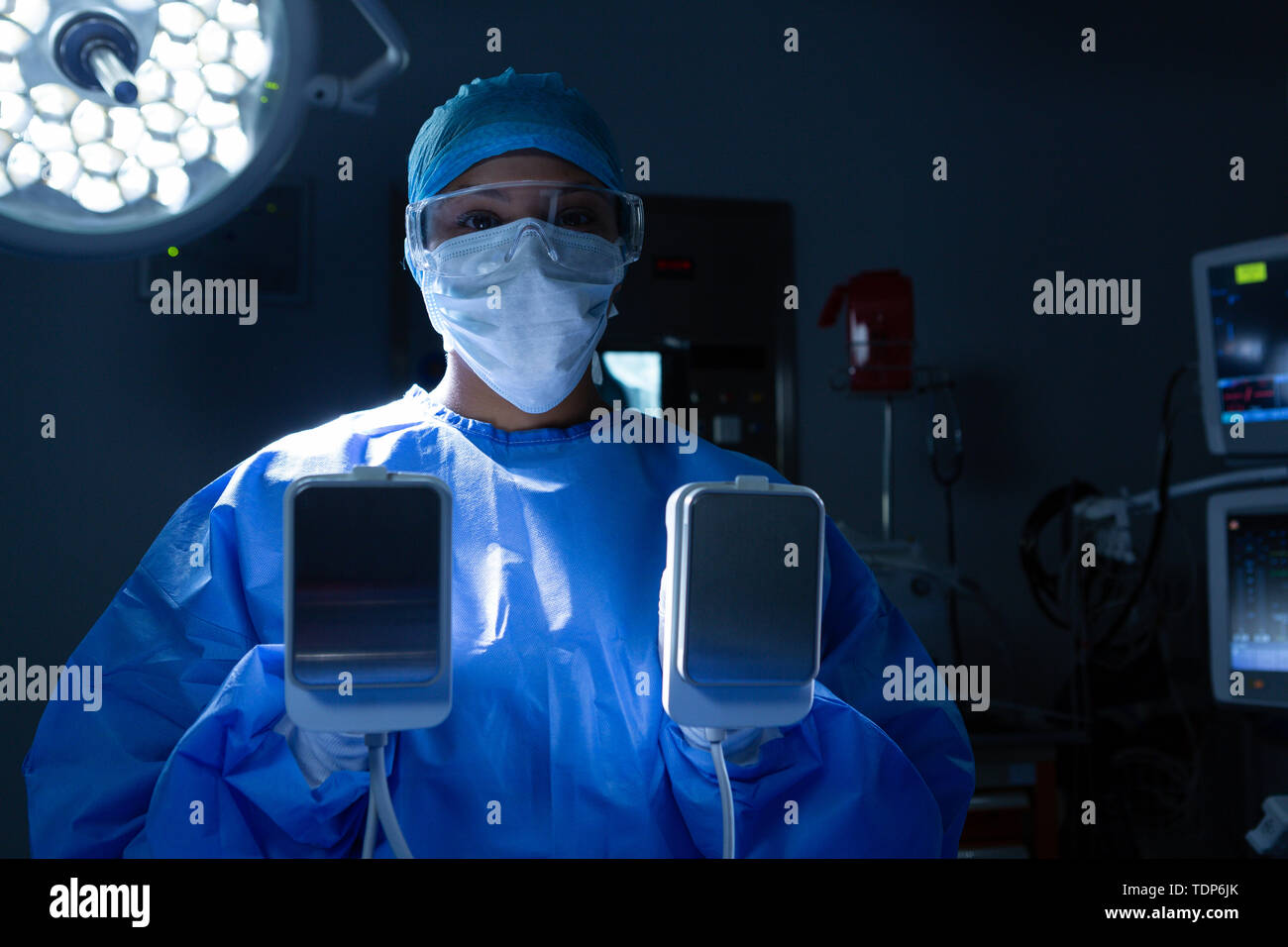 Female surgeon holding defibrillator in operation theater at hospital ...