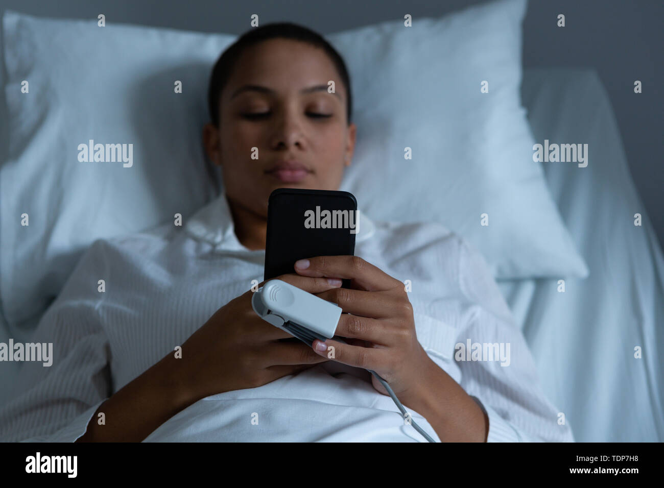 Female patient using mobile phone while lying on bed in the ward Stock ...