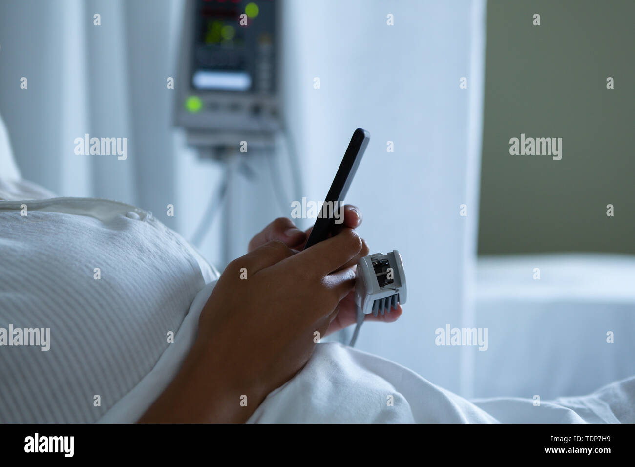 Female patient using mobile phone while lying in bed Stock Photo - Alamy