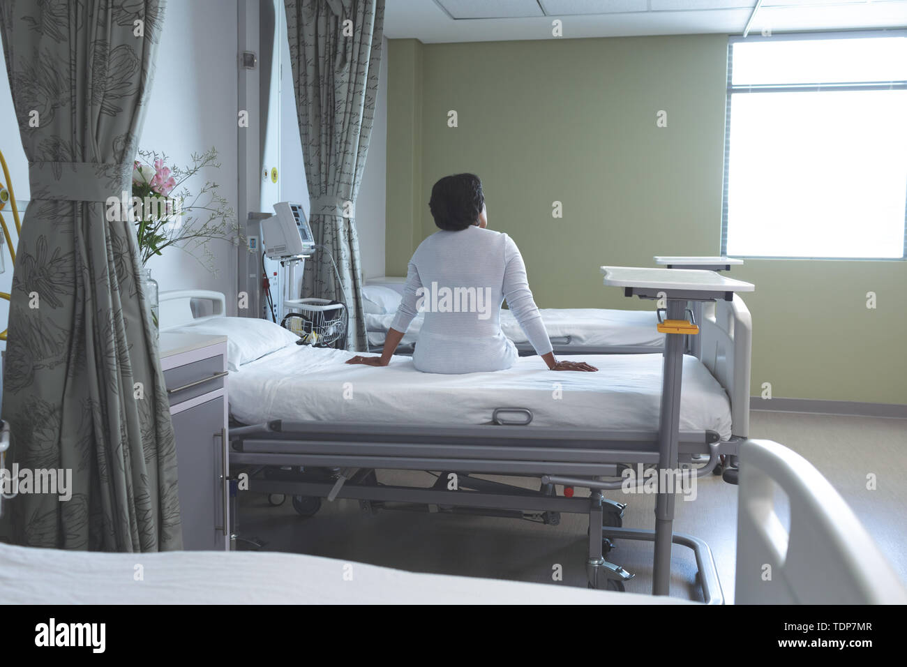 Female patient sitting on bed in the ward at hospital Stock Photo - Alamy