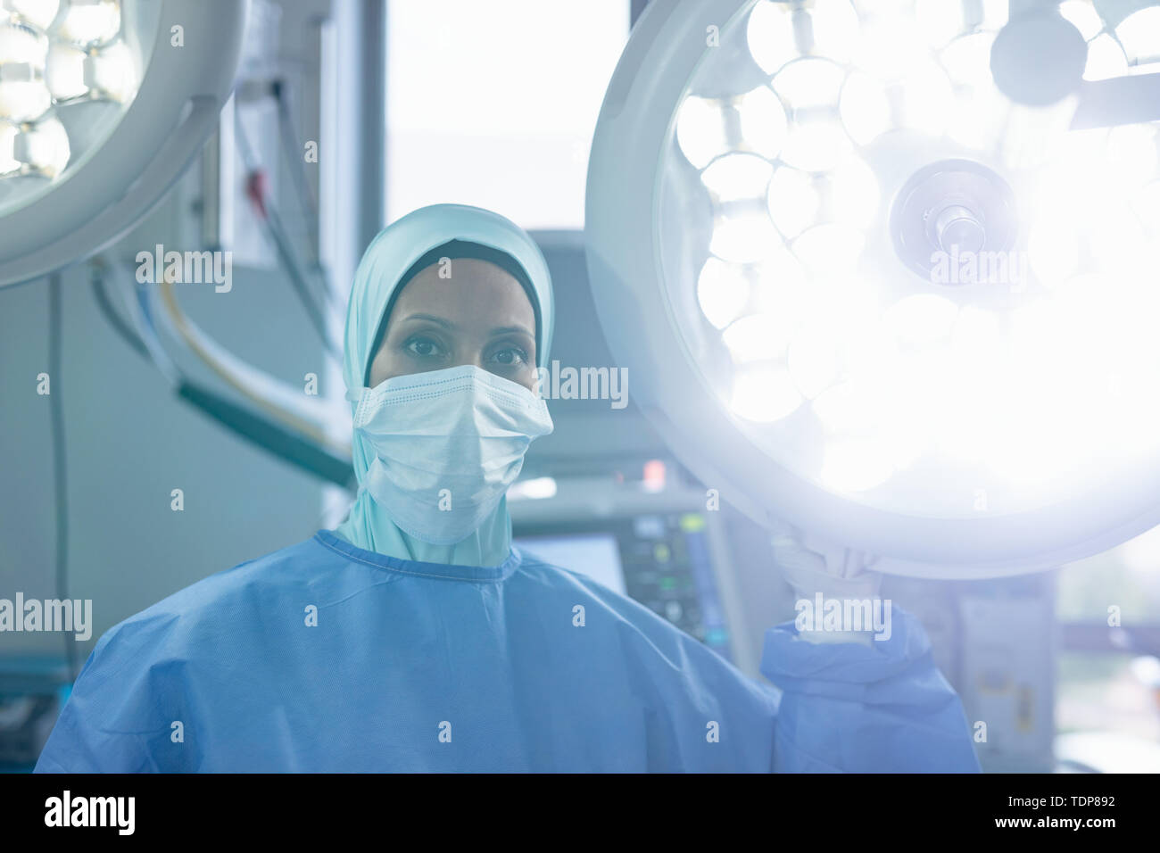 Female surgeon holding surgical light while standing in operation room ...