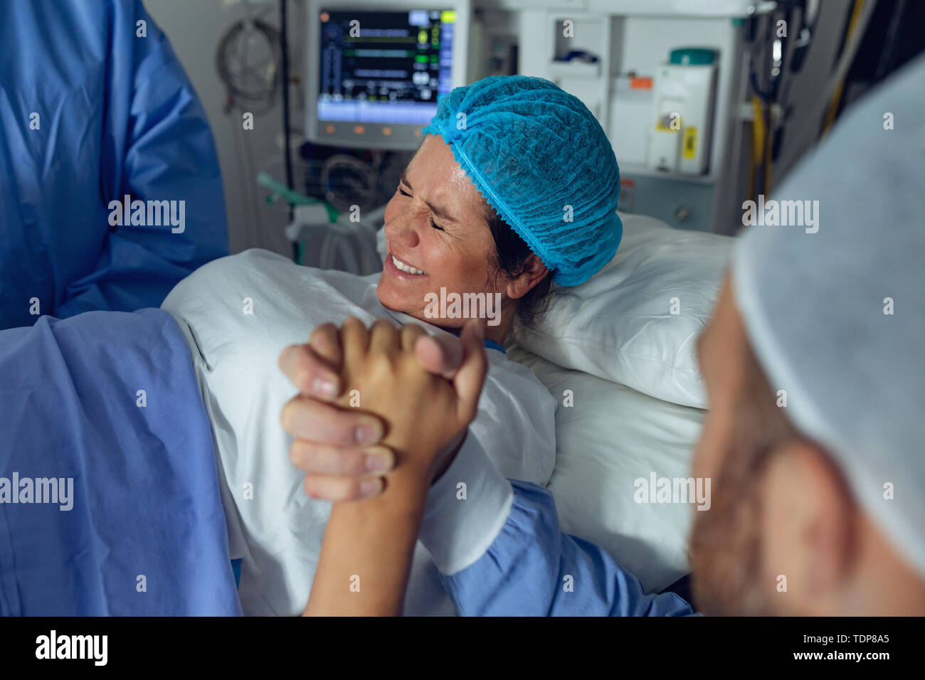 Surgeon examining pregnant woman during delivery while man holding her ...