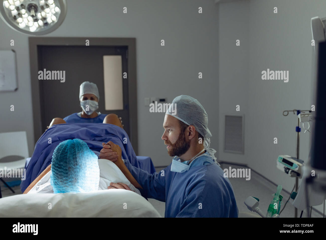 Surgeon examining pregnant woman during delivery while man holding her ...