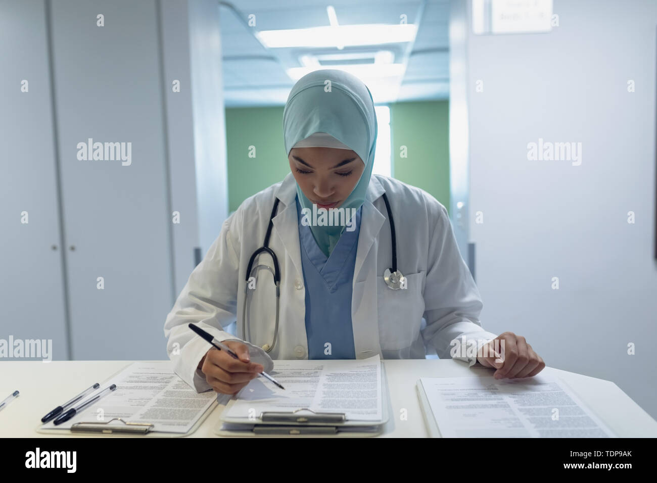 Female doctor reading documents at reception Stock Photo - Alamy