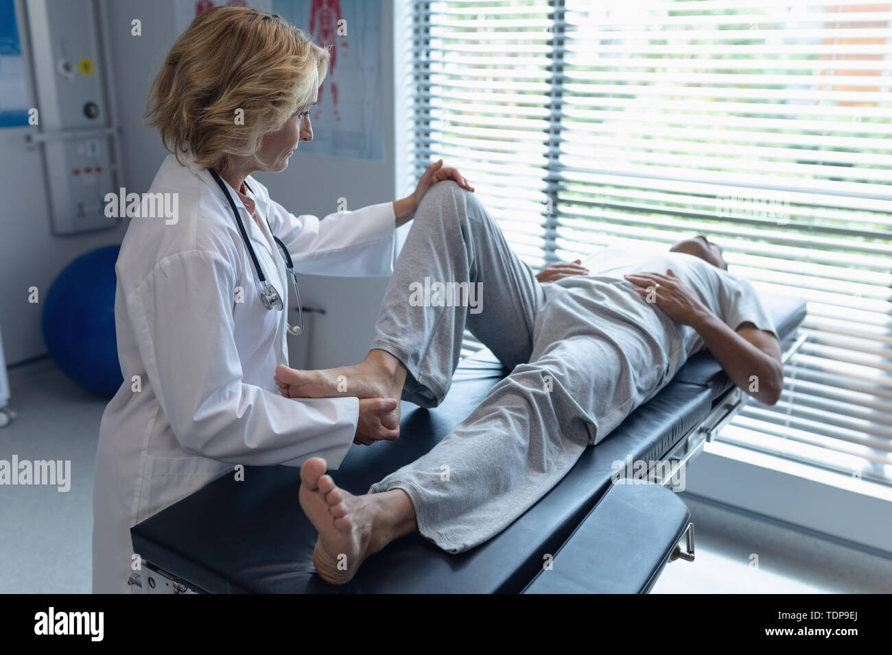 Female doctor examining male patient leg in hospital Stock Photo - Alamy