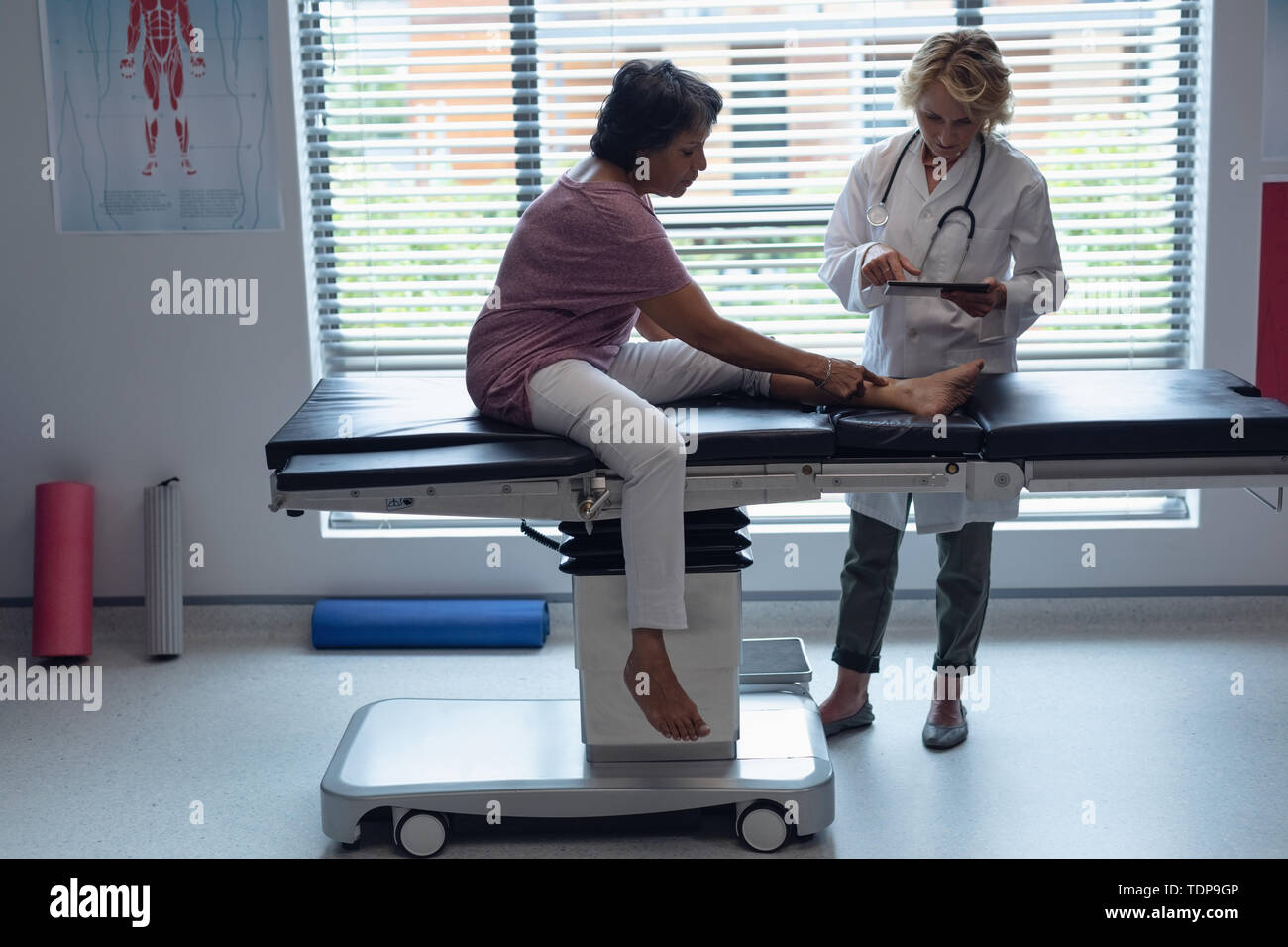 Female doctor using digital tablet while examining her patient Stock ...