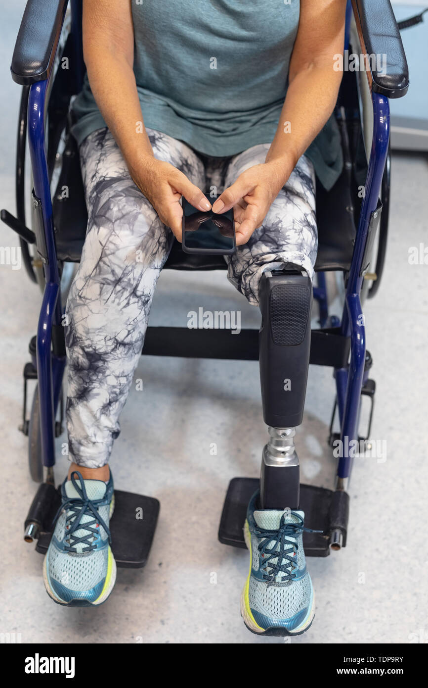 Disabled female patient using mobile phone on wheelchair in the ...