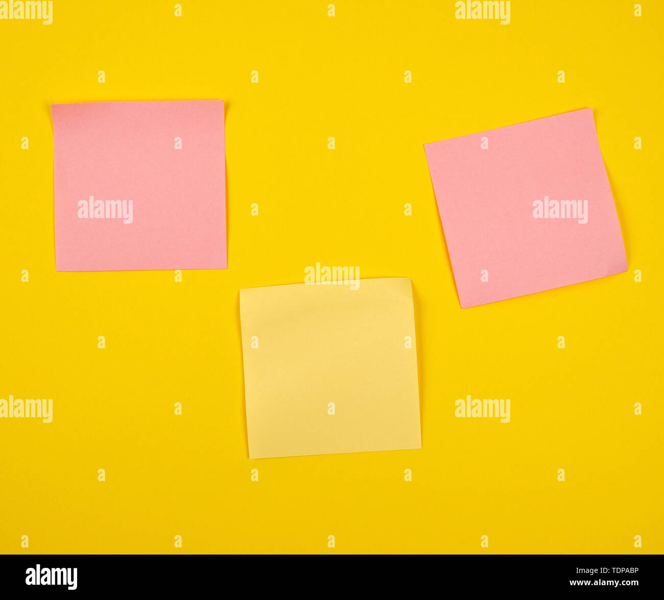 pink and yellow paper stickers pasted on yellow background, close up ...