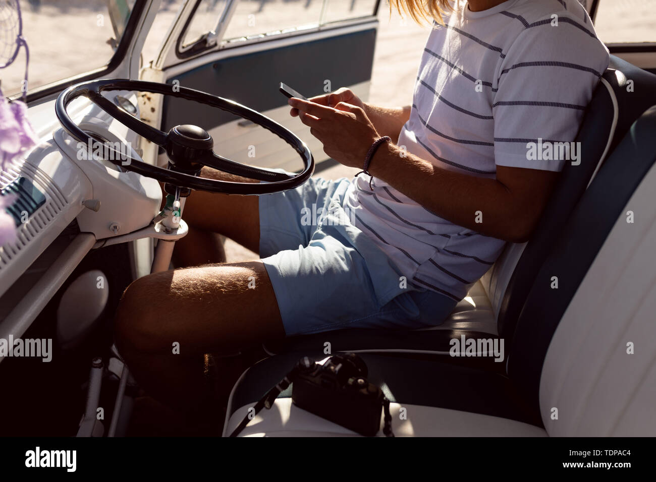 Young man using mobile phone in camper van at beach Stock Photo - Alamy