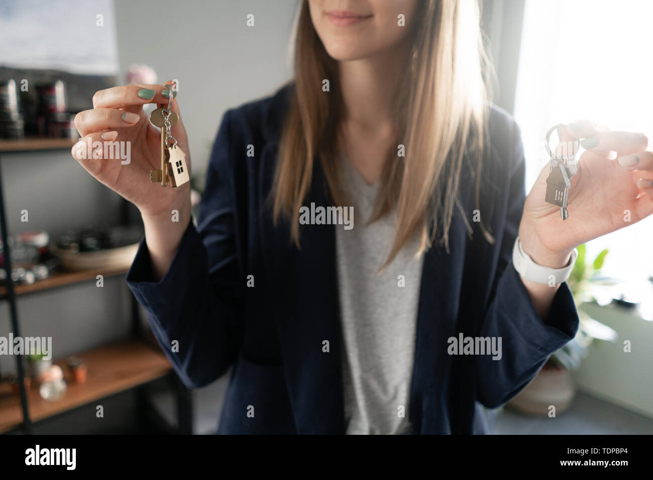 two house keys in womans hands. Young pretty woman smiles. Modern light ...