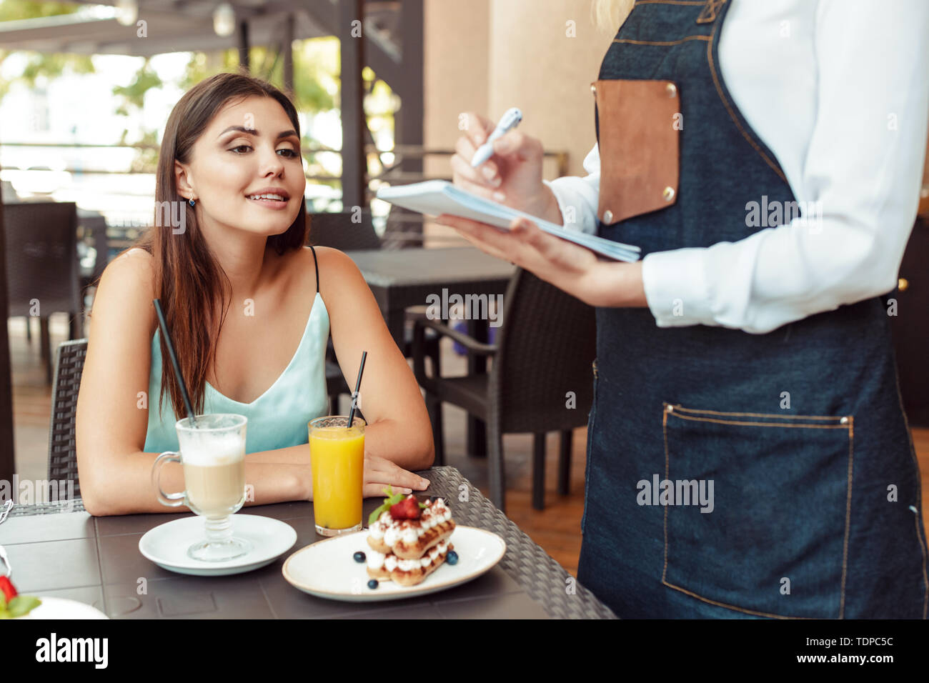 Waitress server helping client in cafe Stock Photo - Alamy
