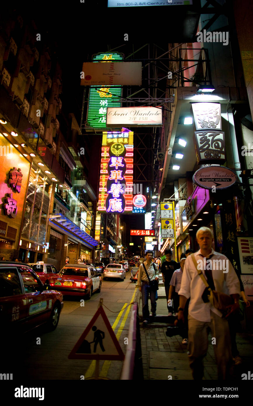 Pedestrians walking along an illuminated city street at night Stock ...