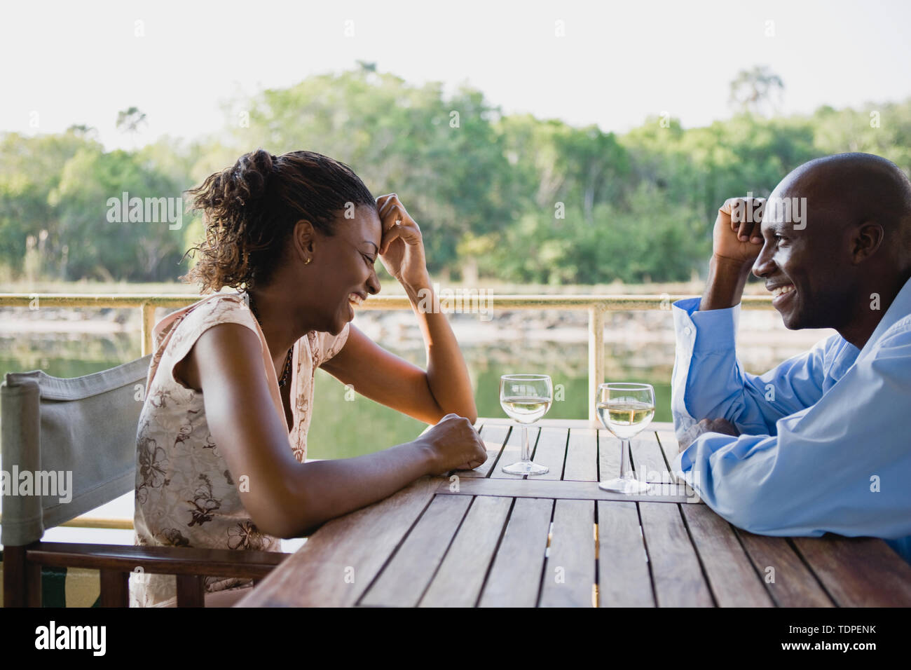 Happy mid-adult couple seated at an outdoor table Stock Photo - Alamy