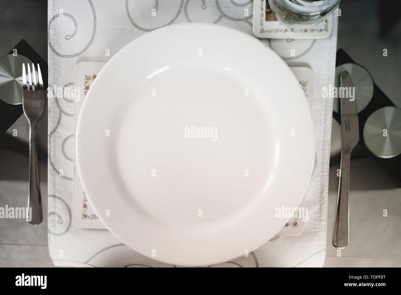 A top down shot looking down at a white plate next to silver knife and ...