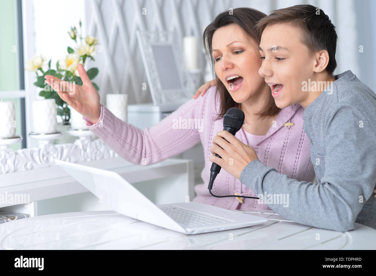 Portrait of emotional mother and son singing karaoke Stock Photo - Alamy