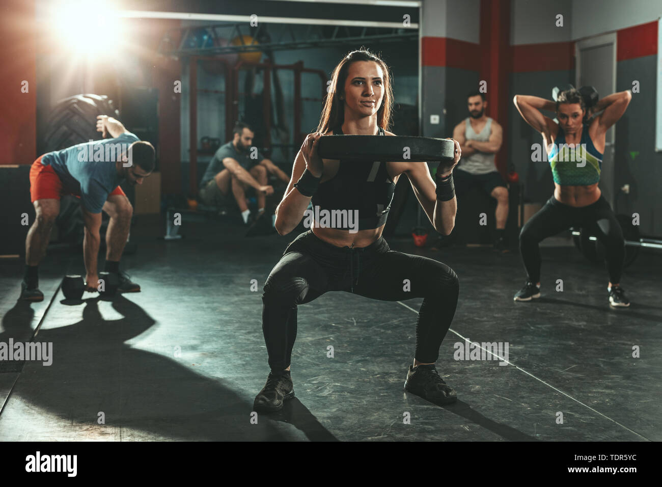 Young muscular cute woman doing hard exercise with heavy plate at the ...