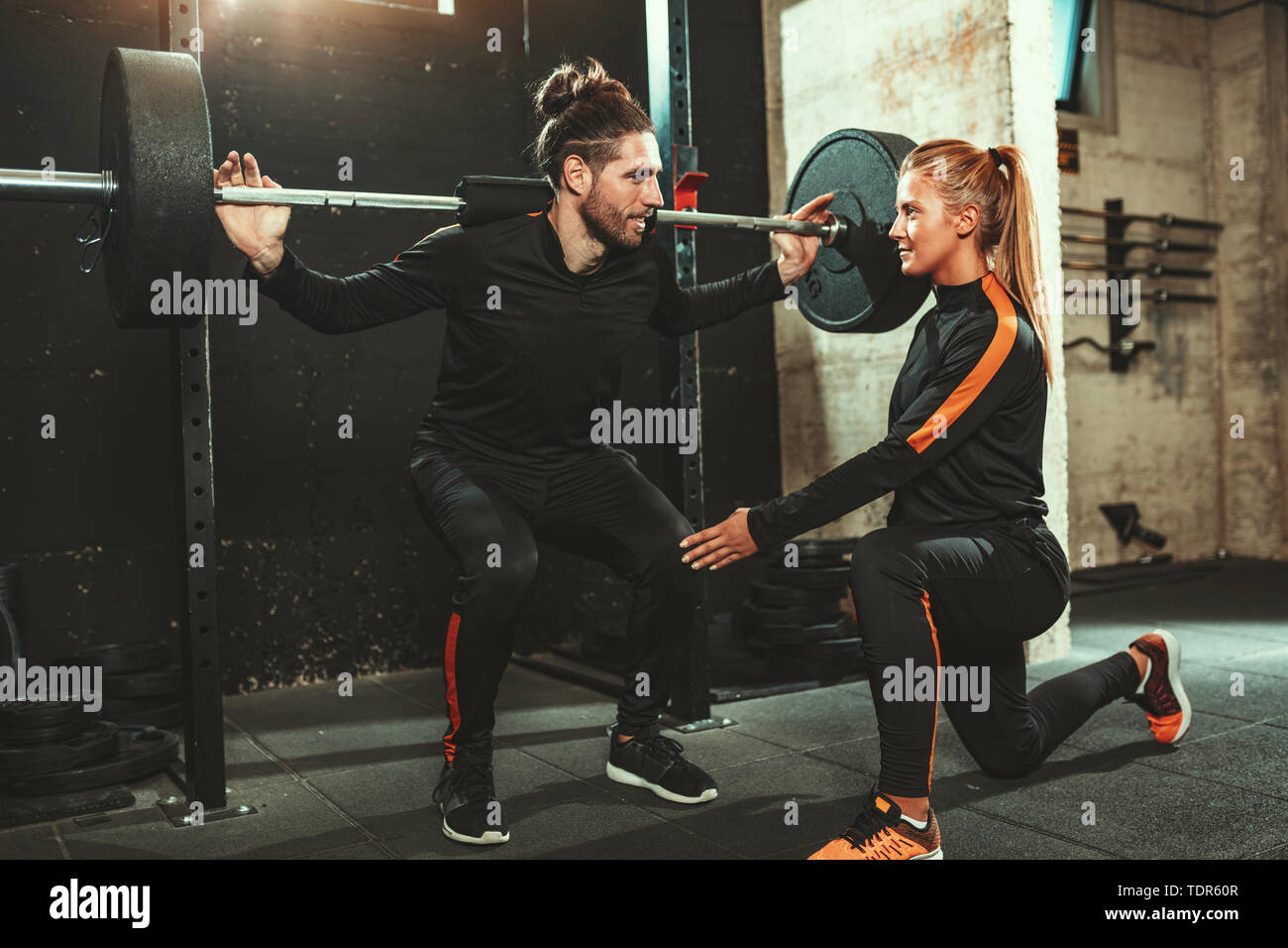 Handsome young muscular man is doing squat exercises with barbell ...
