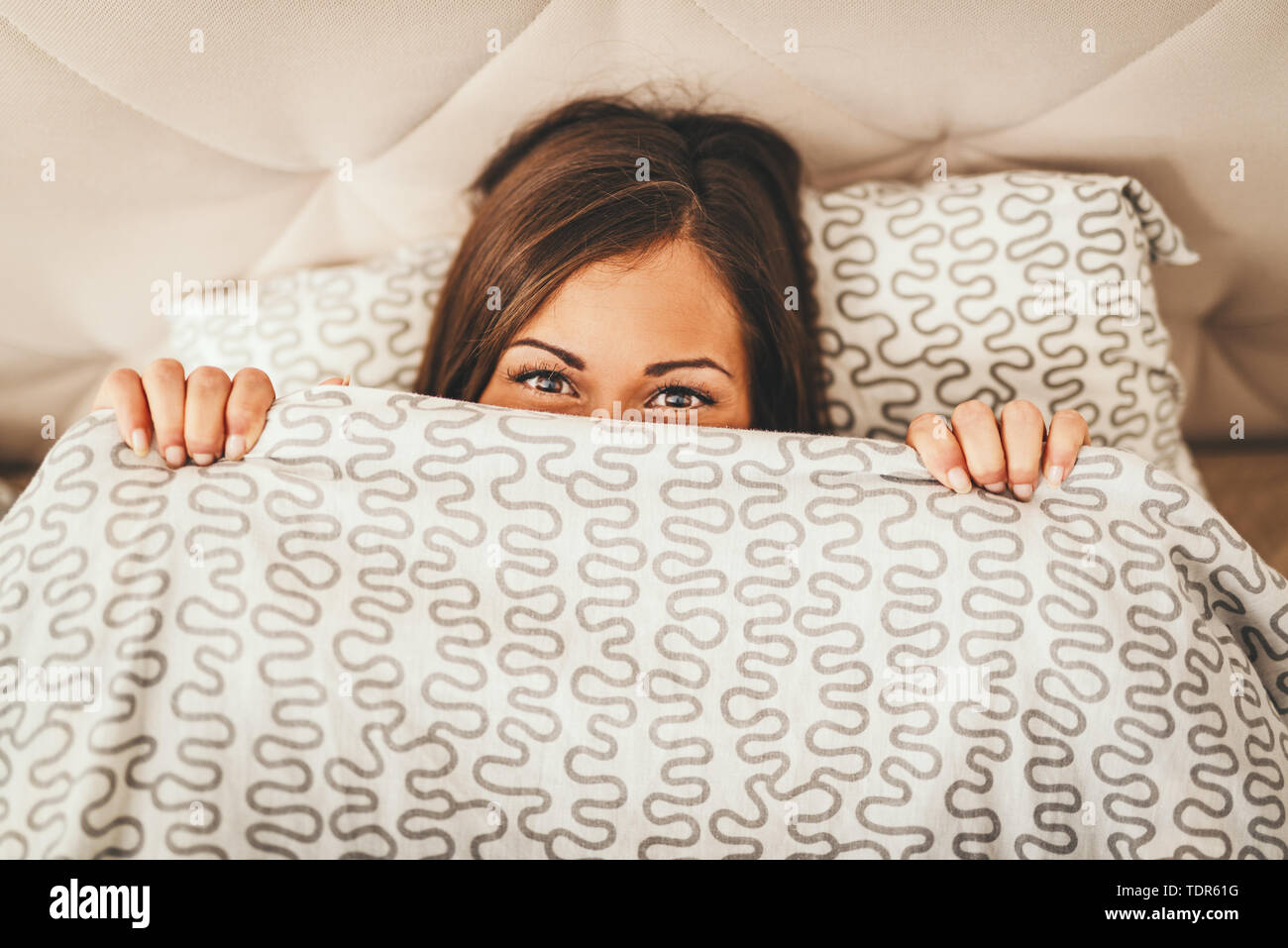 Beautiful smiling young woman is lying down on the bed in the morning ...