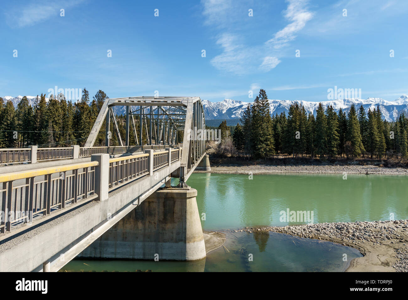 metal bridge over the river with green water in spring with mountains ...