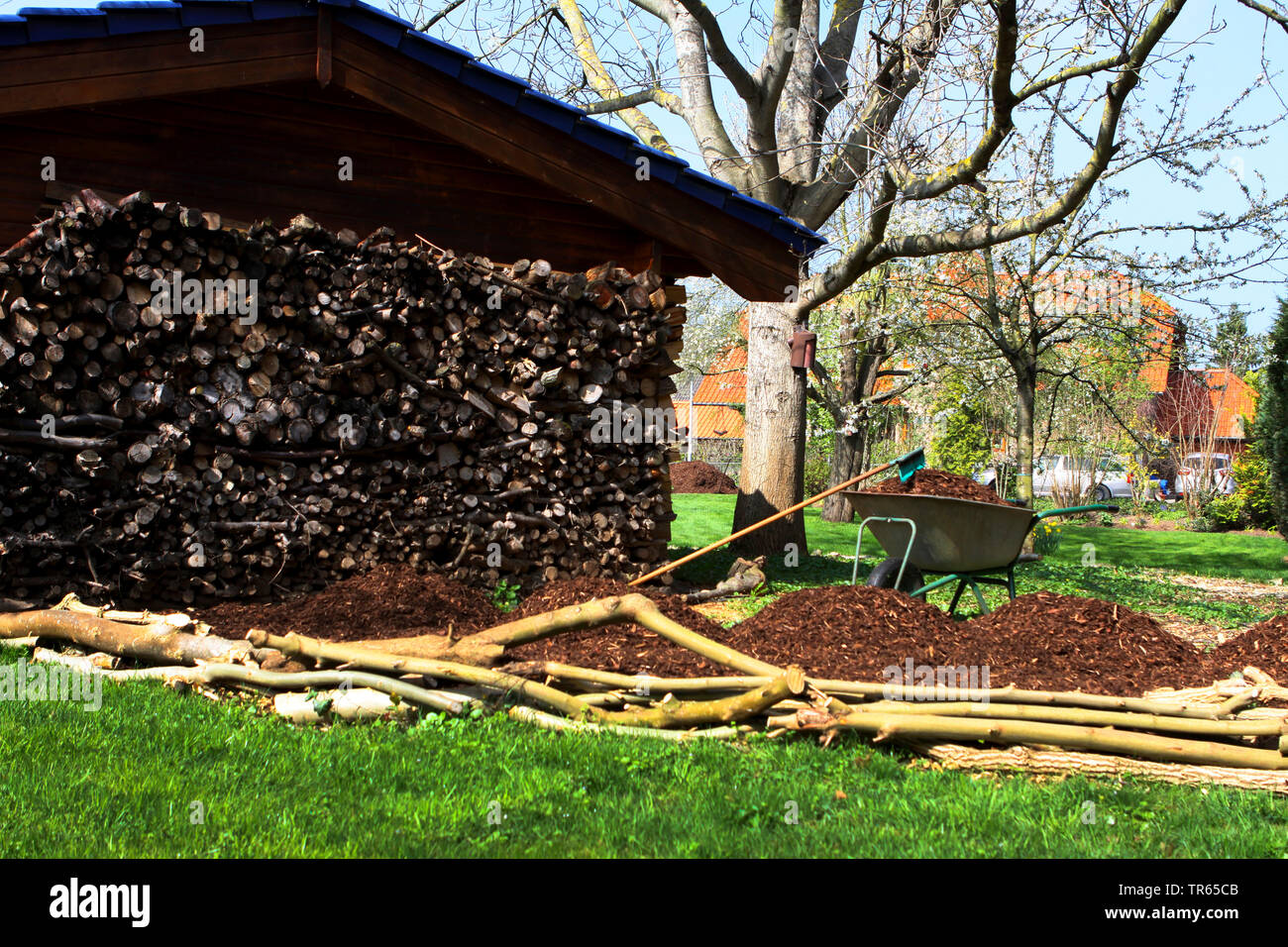 wood stack, mount of bark mulch and barrow in a garden, Germany, North ...