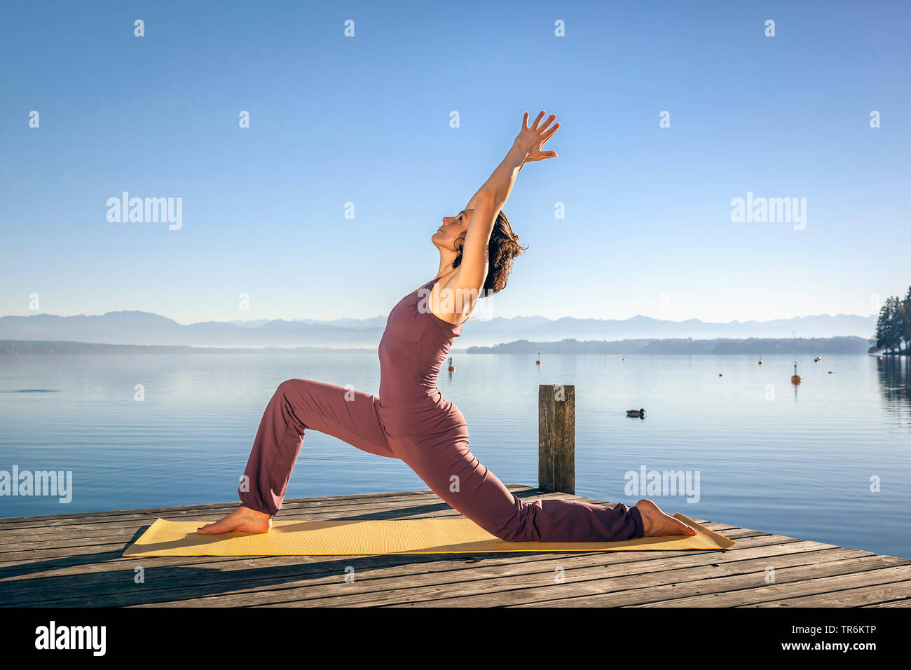 woman doing yoga exercises at a lake, Anjaneyasana, Germany, Bavaria ...