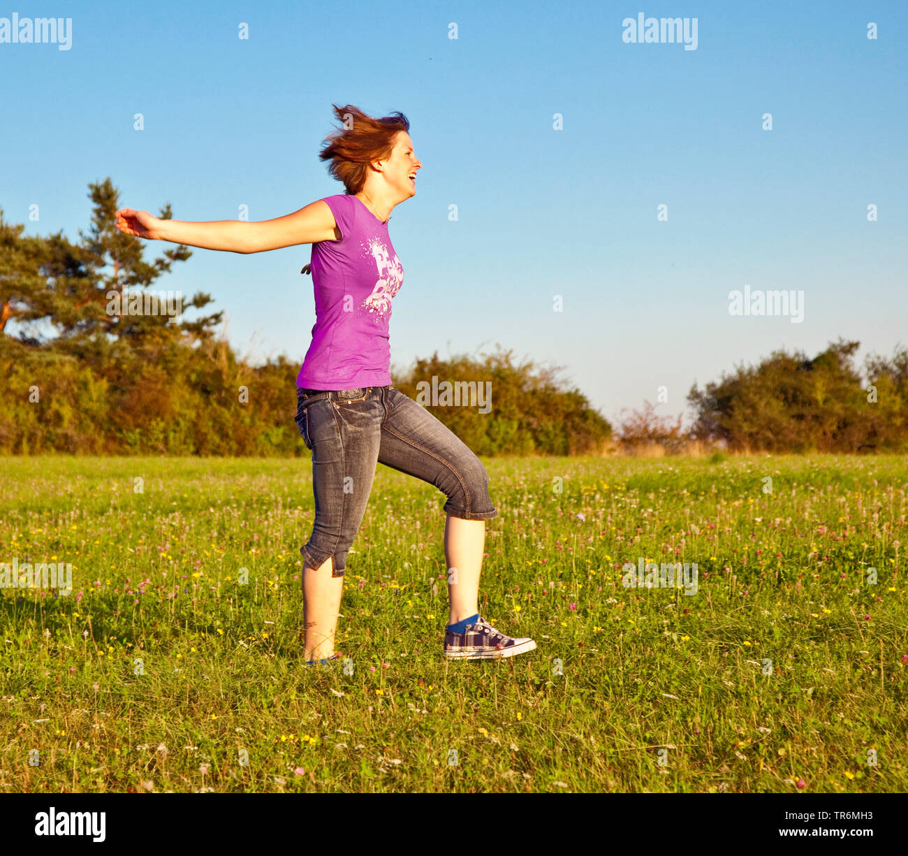 young girl jumping across a meadow Stock Photo - Alamy