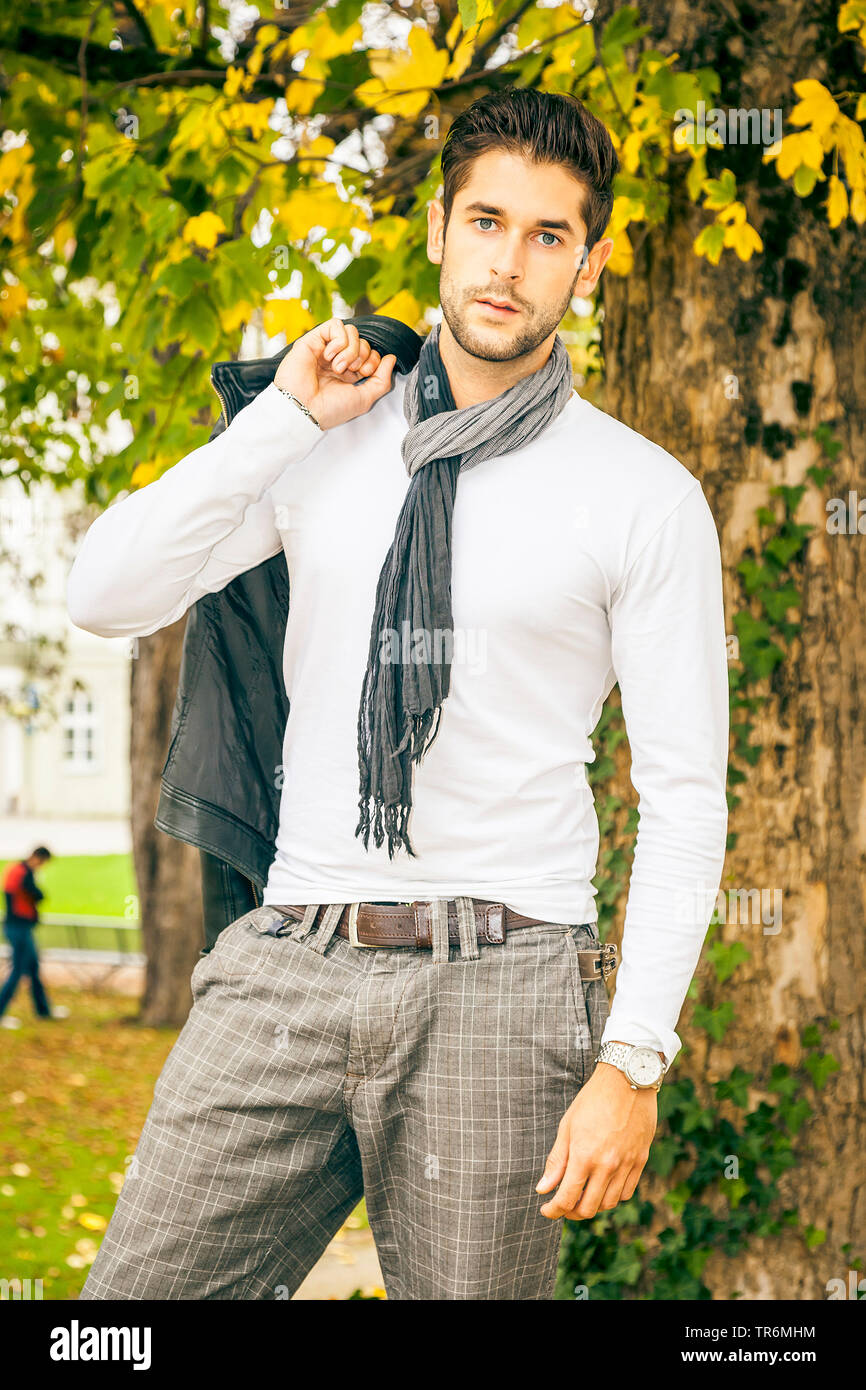young attractive man in nature, with leather jacket over the shoulder ...