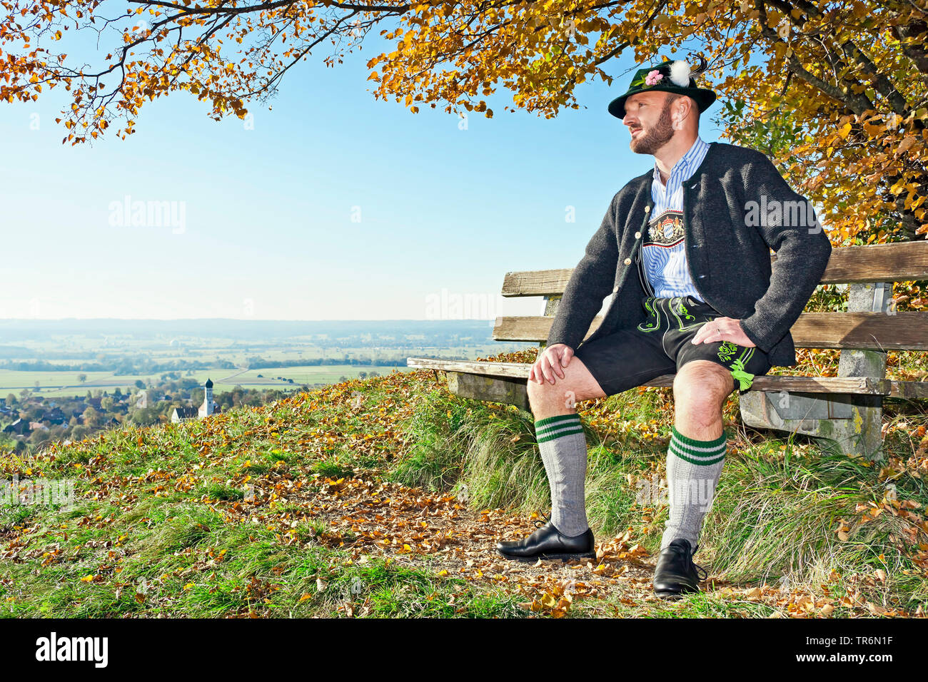 traditional clothed Bavarian man with Tyrolean hat sitting on a bench ...
