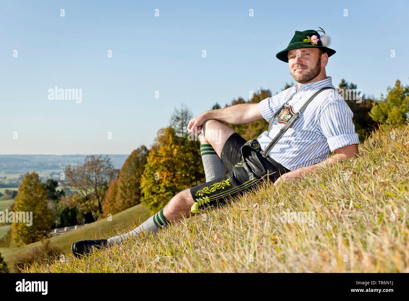 traditional clothed Bavarian man sitting on an alpine pasture and ...