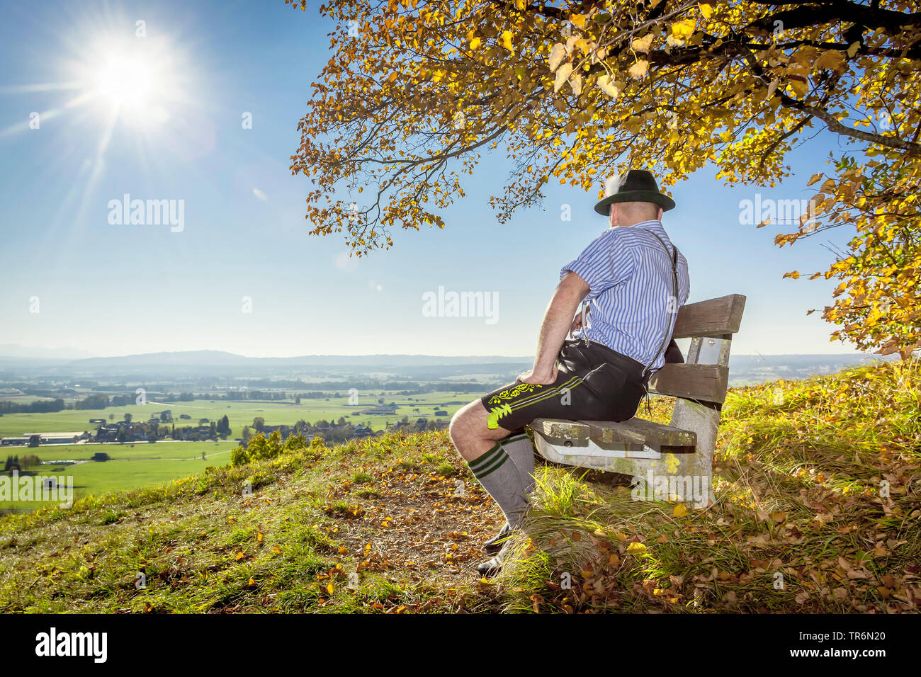 traditional clothed Bavarian man with Tyrolean hat sitting on a bench ...