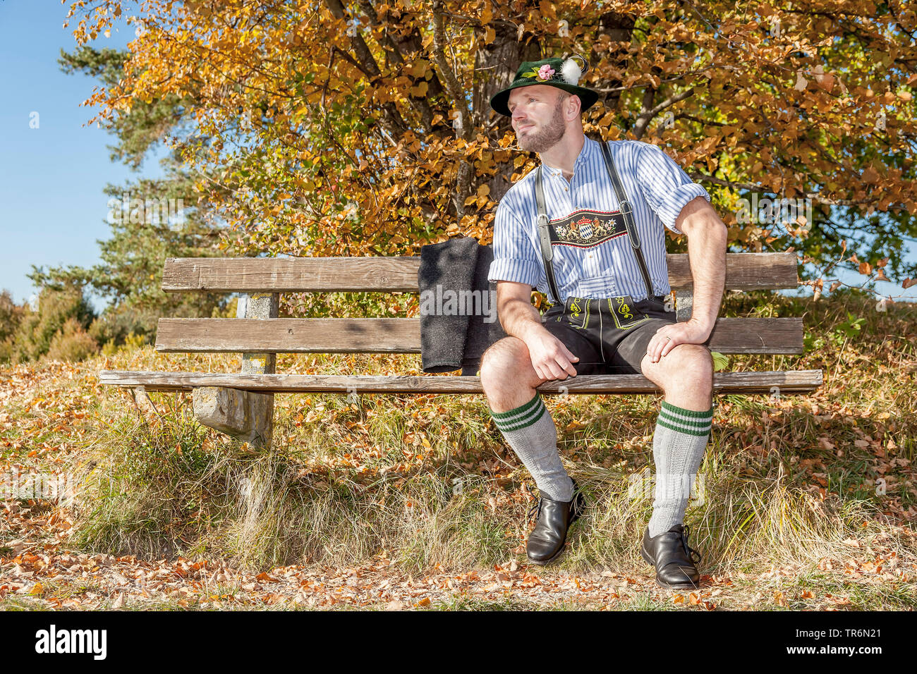 traditional clothed Bavarian man with Tyrolean hat sitting on a bench ...