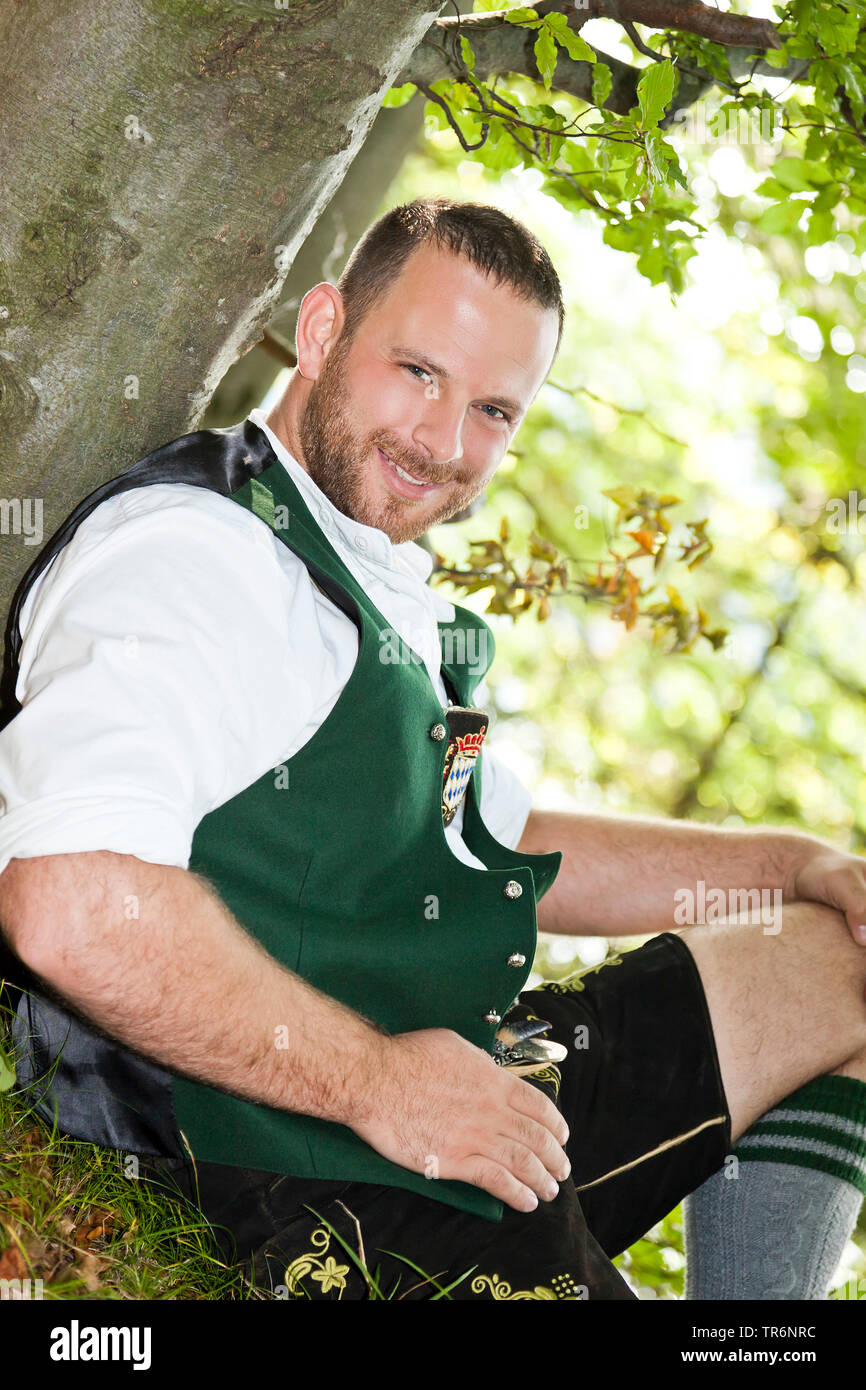 traditional clothed Bavarian man sitting in a forest at a tree, Germany ...