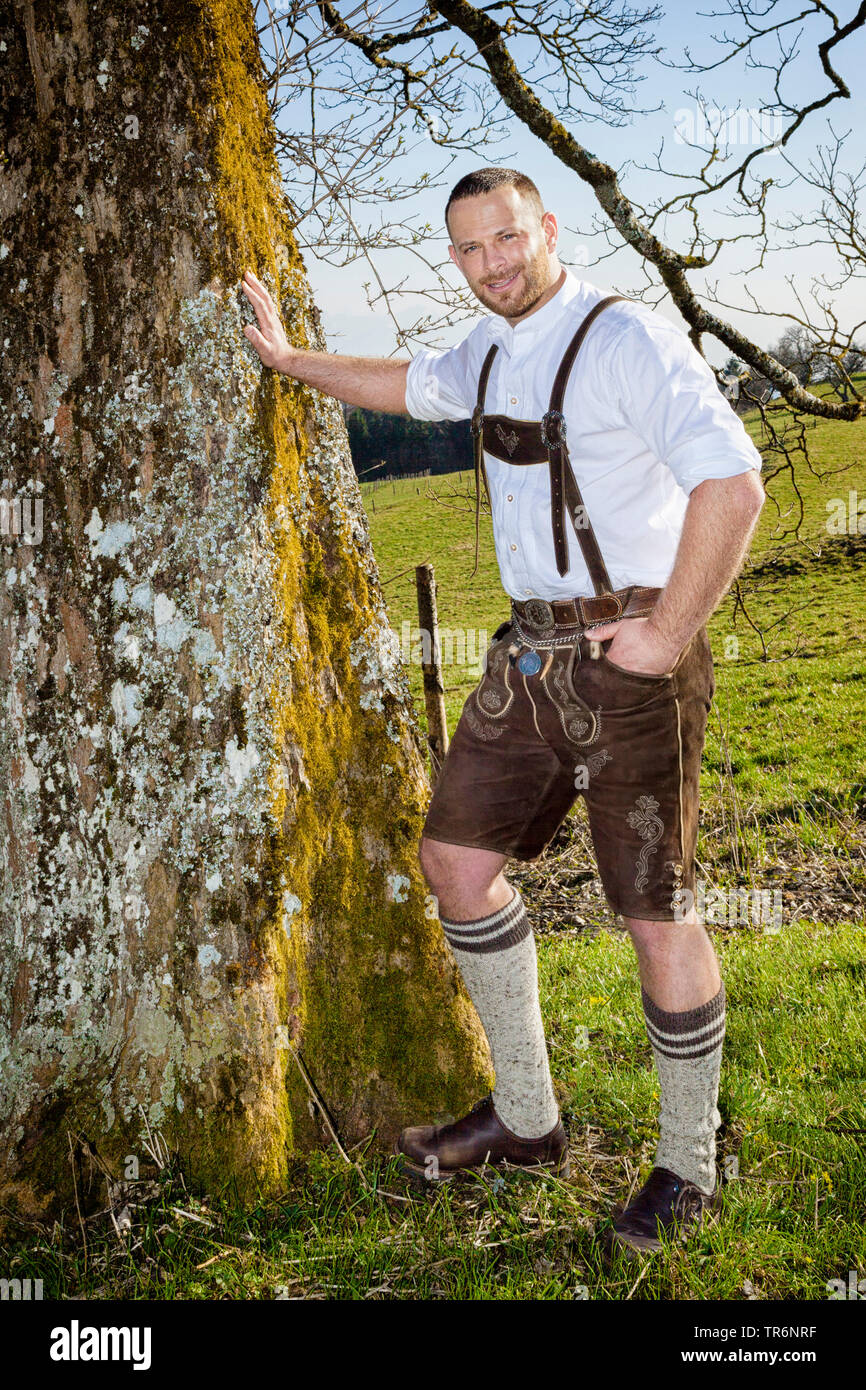 traditional clothed Bavarian man standing at a tree, Germany, Bavaria ...