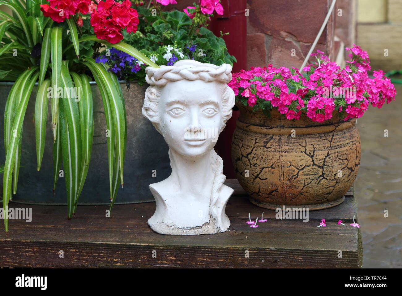 Gypsum statue on a wooden table near flowers Stock Photo - Alamy