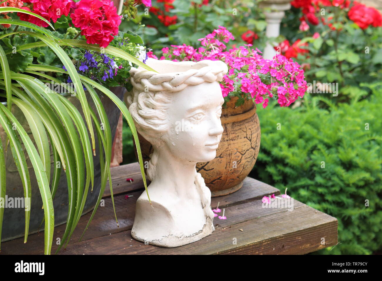 Gypsum statue on a wooden table near flowers Stock Photo - Alamy