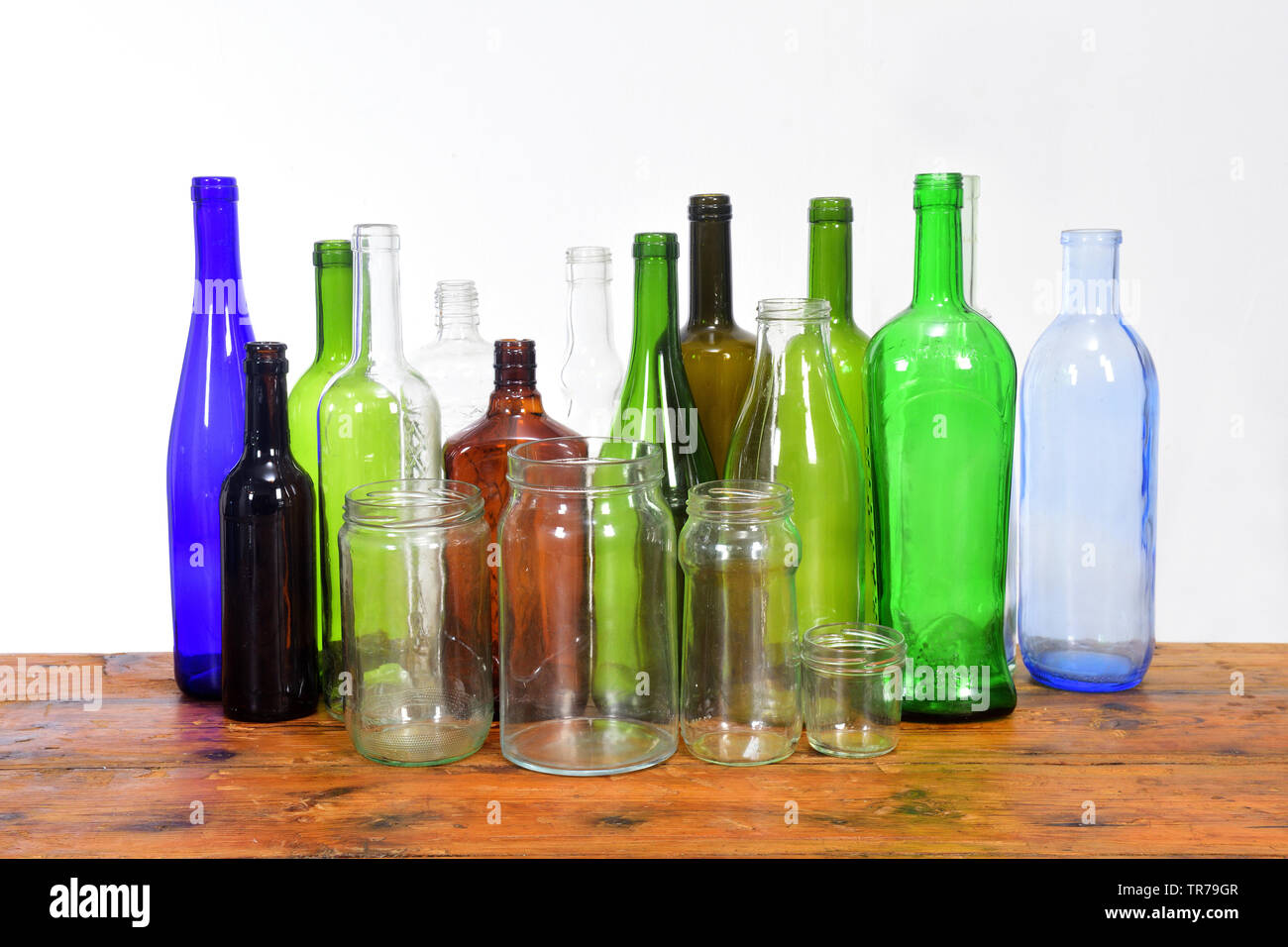 group of bottles and glass jars on a wooden table with white background ...