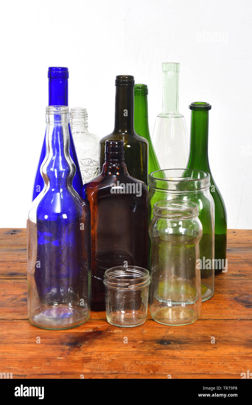 group of bottles and glass jars on a wooden table with white background ...