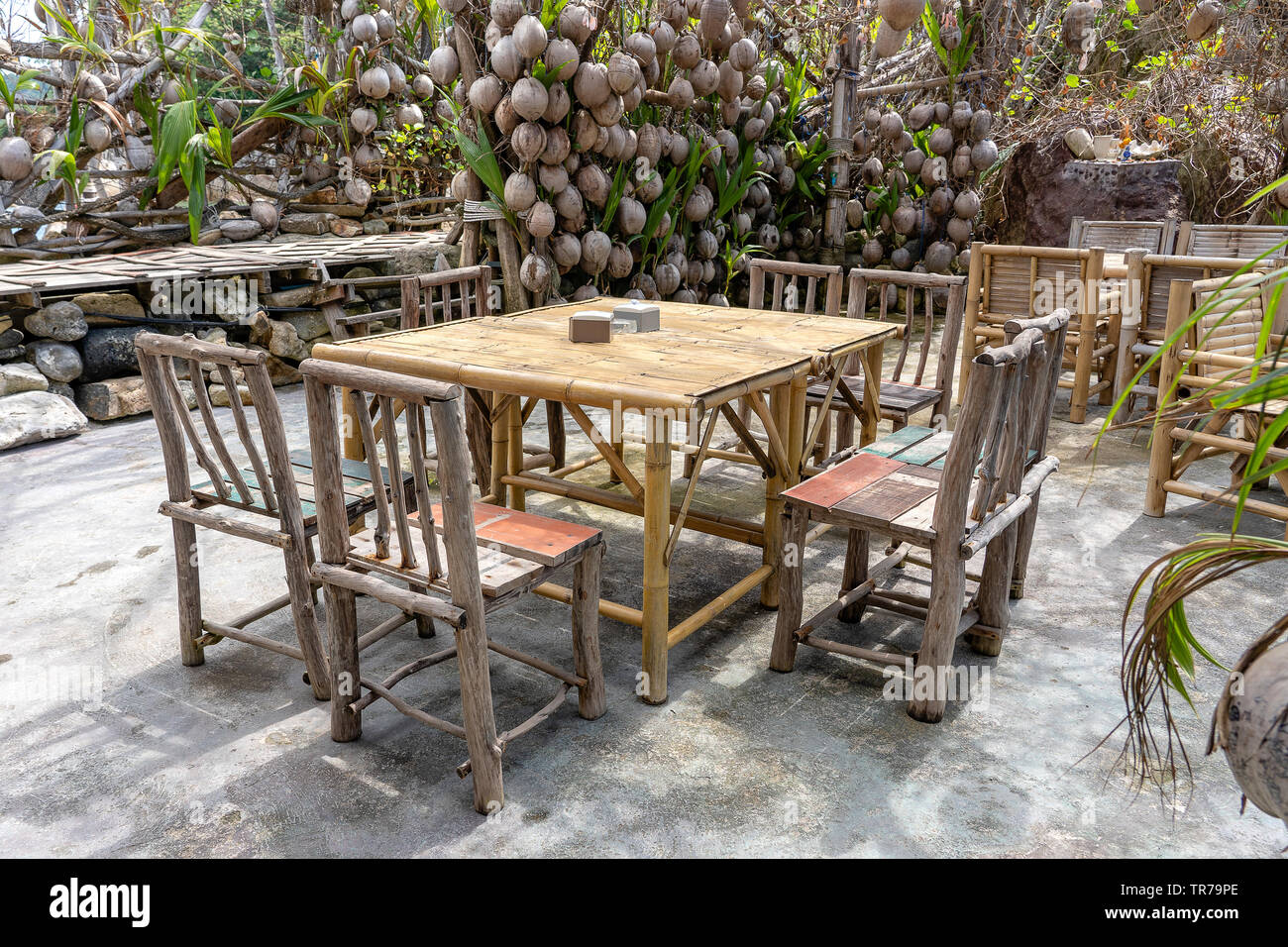 Wooden table and chairs in empty beach cafe next to sea in garden. Close up. Island Koh Phangan ...