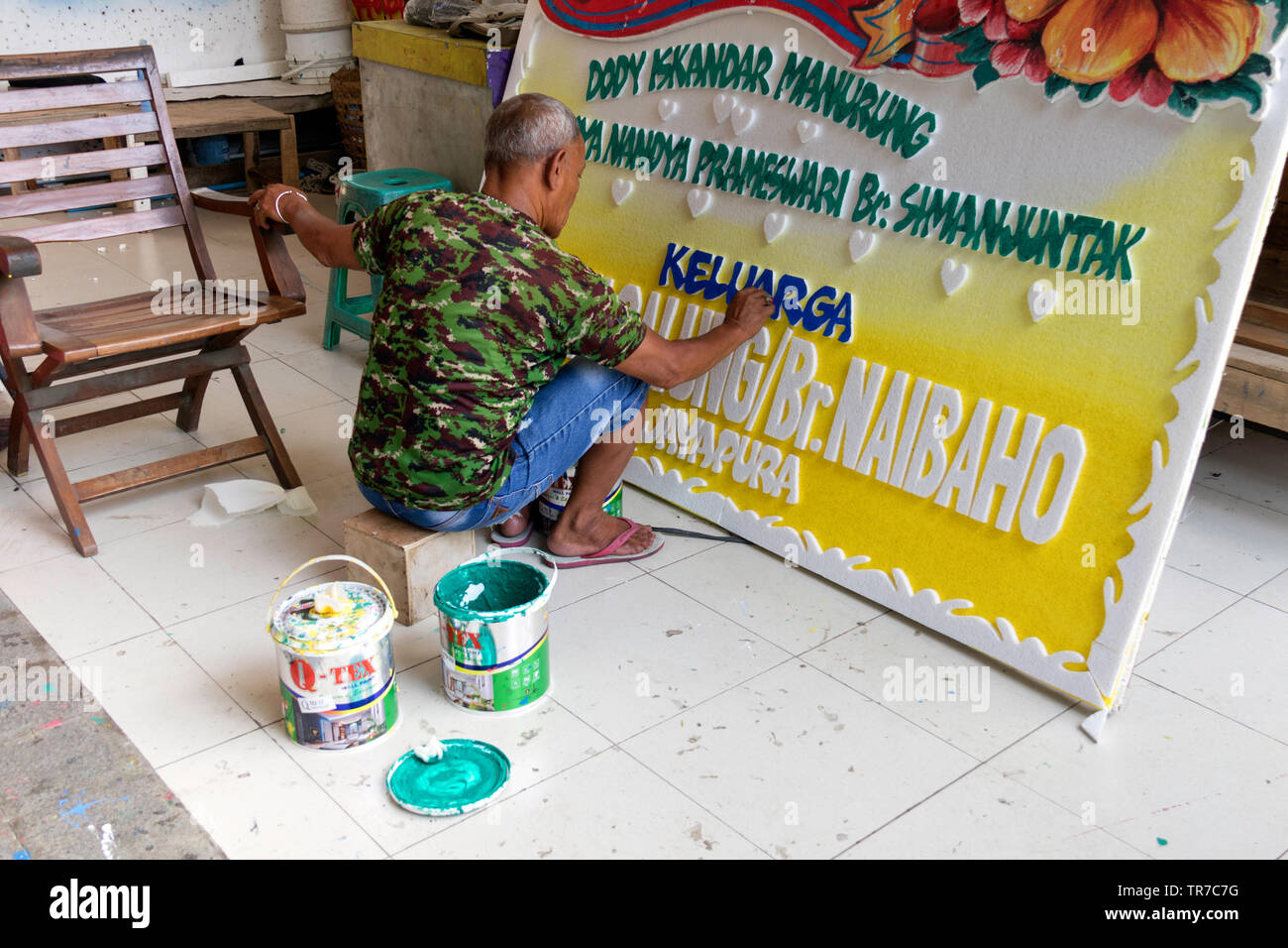 Indonesian man painting event board sign Stock Photo - Alamy