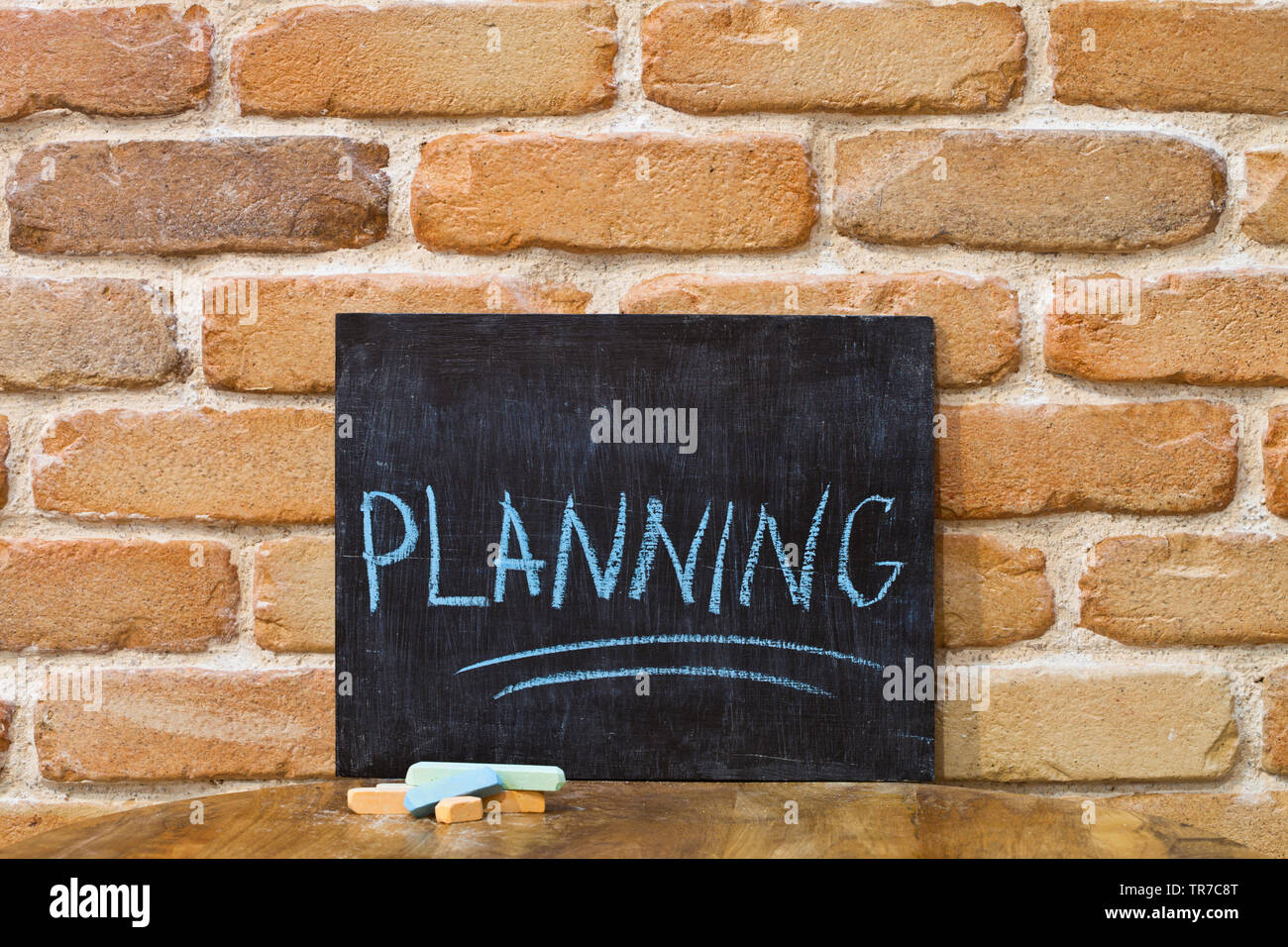 Chalk board with the word PLANNING drown by hand and chalks on wooden ...