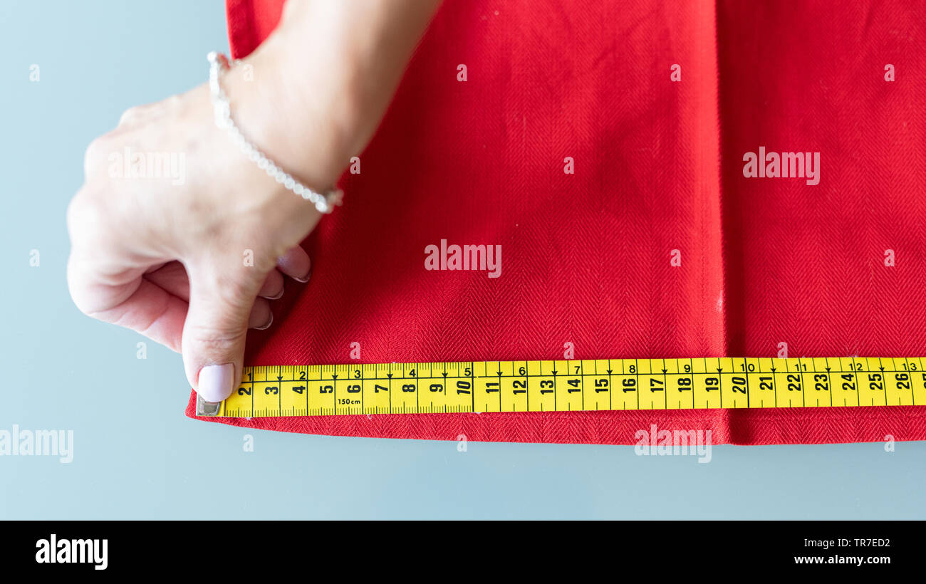Woman measuring a fabric by hand with the meter Stock Photo - Alamy