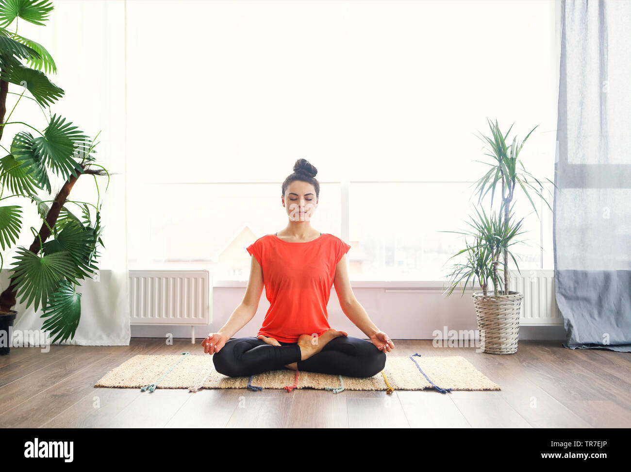 Attractive young brunette woman exercising and sitting in yoga lotus ...