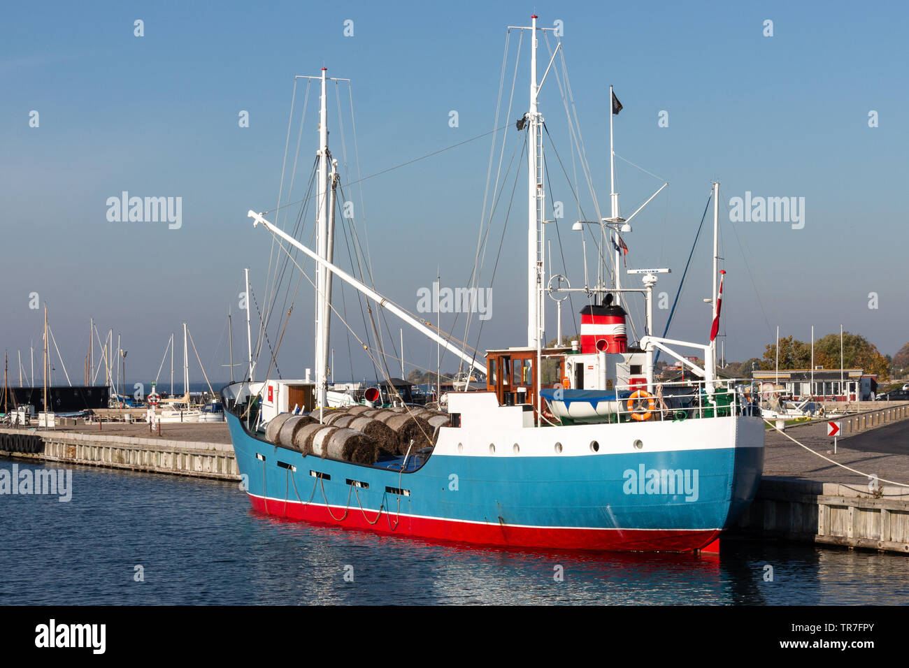 side view of a historic coaster lying at the pier of the port of Stege ...