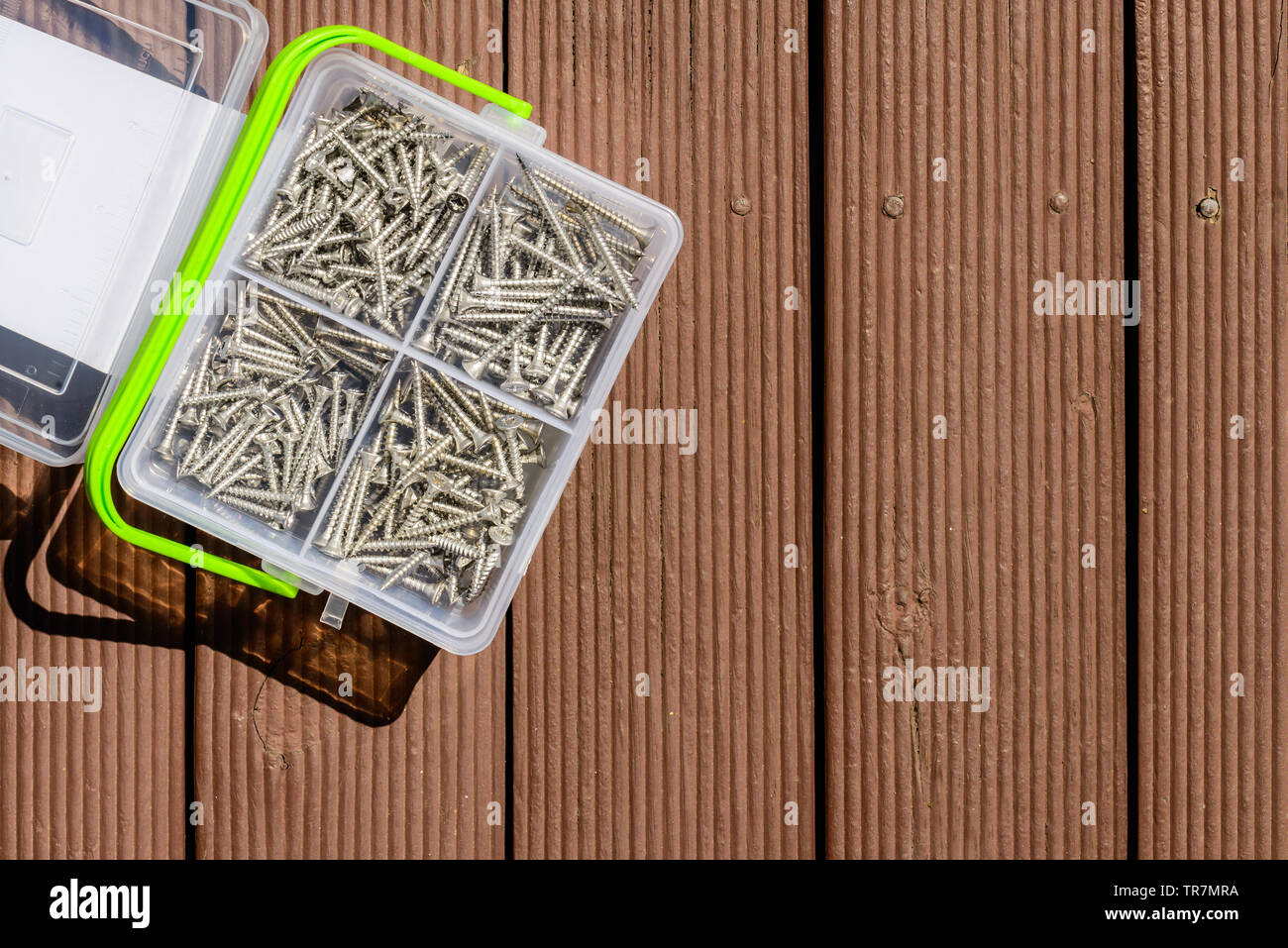 Assorted screws in plastic box on wooden brown deck Stock Photo - Alamy