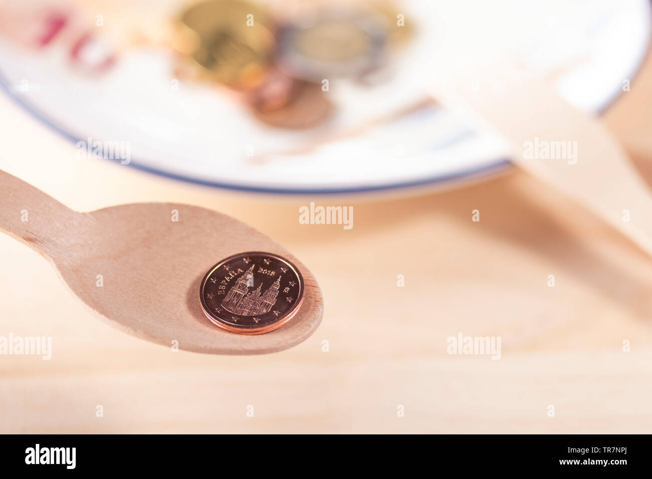 Wooden eco spoon with a coin 2 cents over a white plate with money and ...