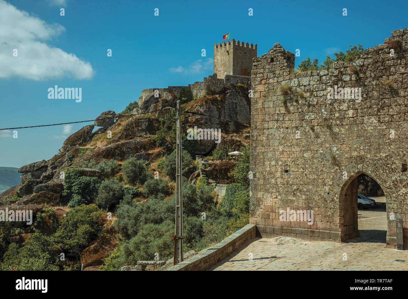 Stone outer wall with gateway and tower of Castle over cliff at ...