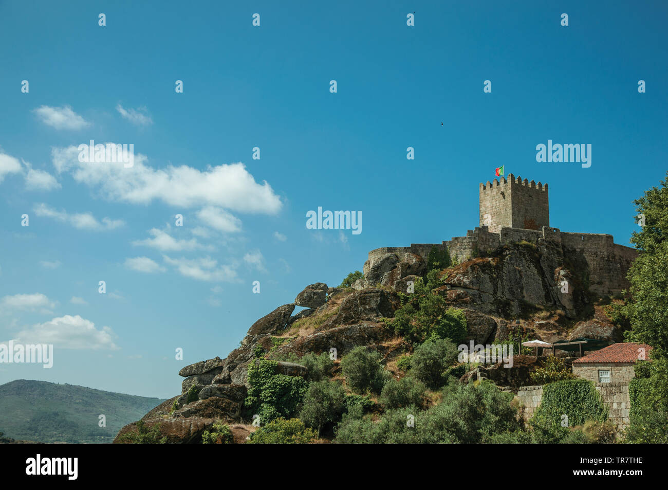 Hilly landscape with stone walls and tower of Castle over rocky cliff ...