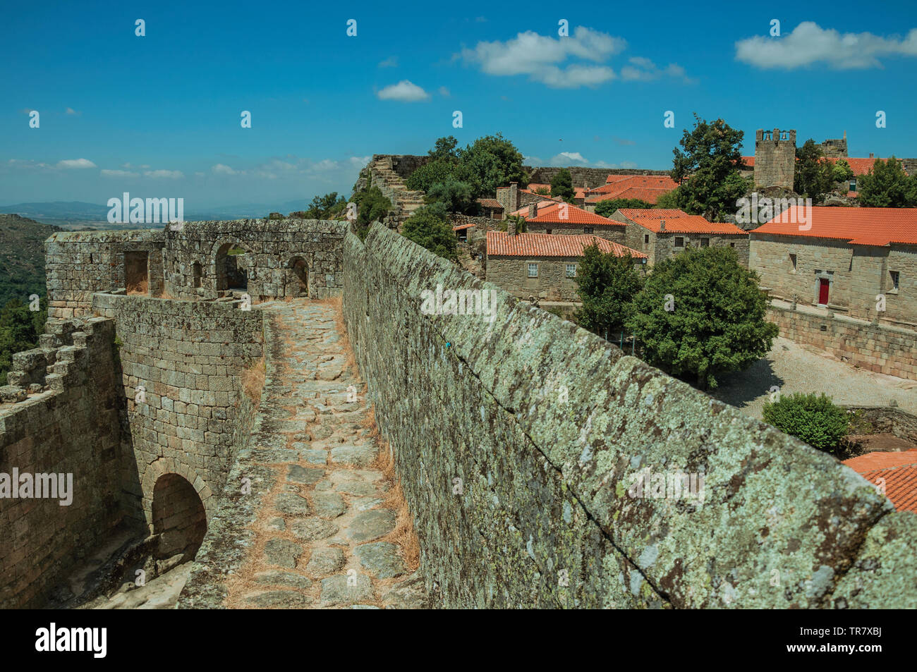 Pathway on stone wall with front gate and hilly landscape at the ...