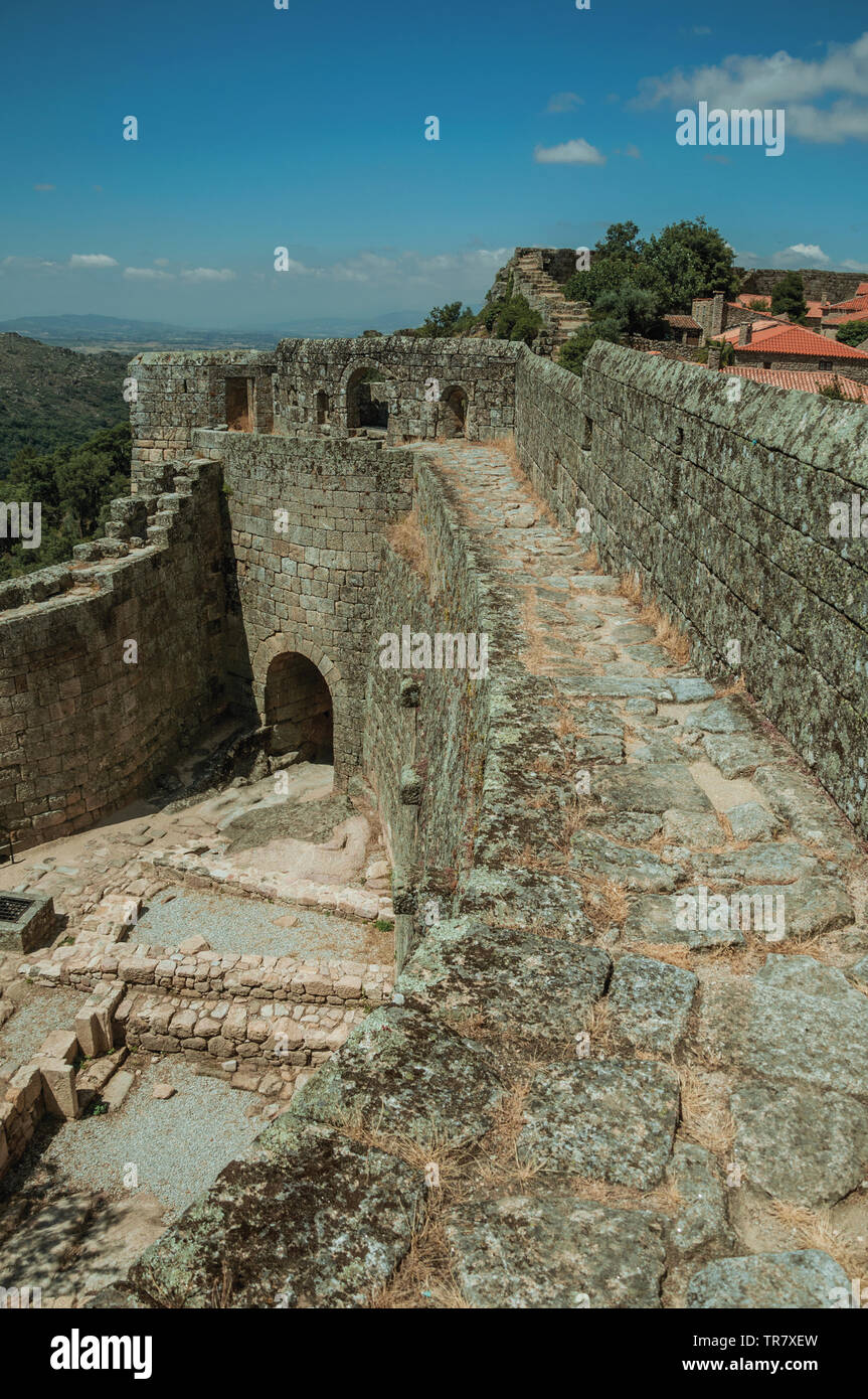 Pathway on stone wall with front gate and hilly landscape at the ...